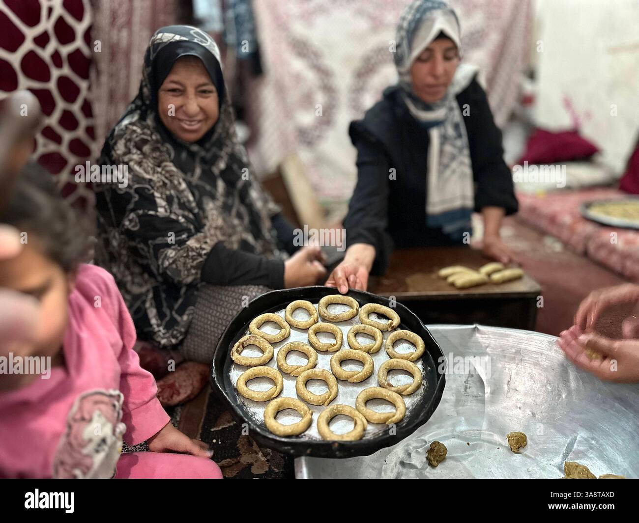 A Palestinian family prepares traditional cookies in preparation for ...