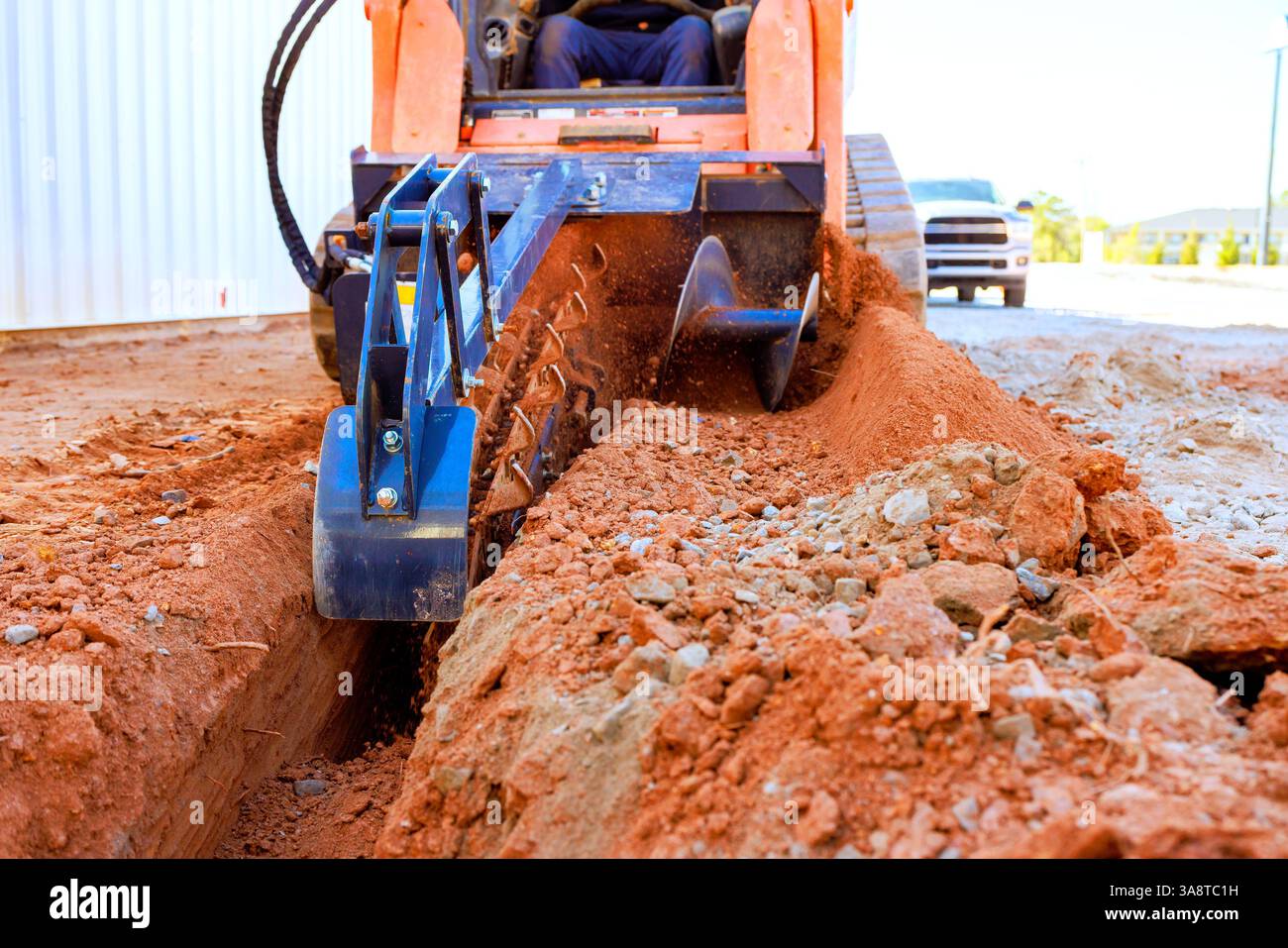 Excavation trencher equipment digs trench in red soil at construction ...