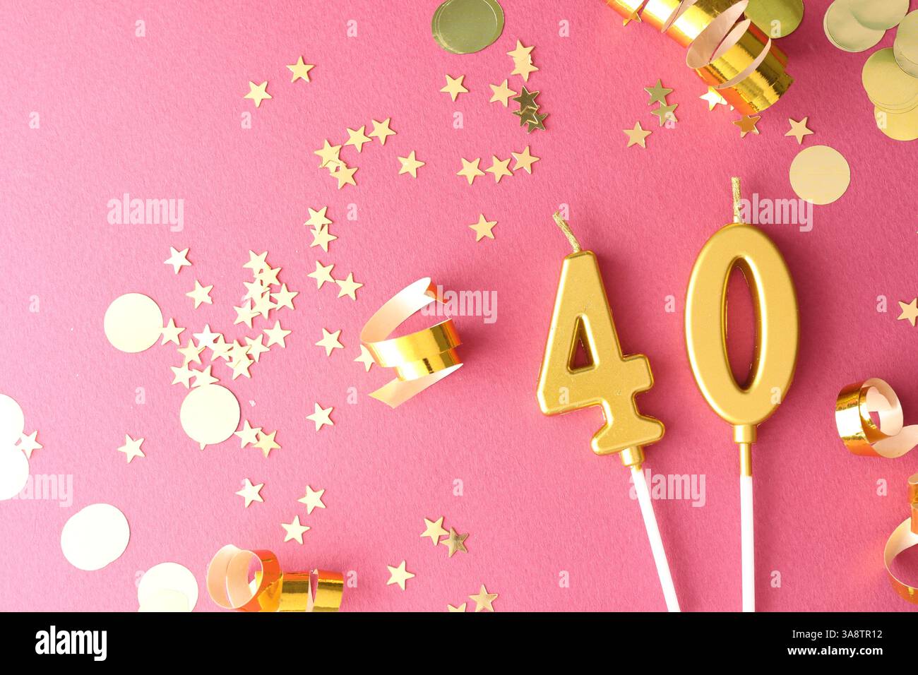 40th birthday. Number shaped candles and confetti on pink background ...