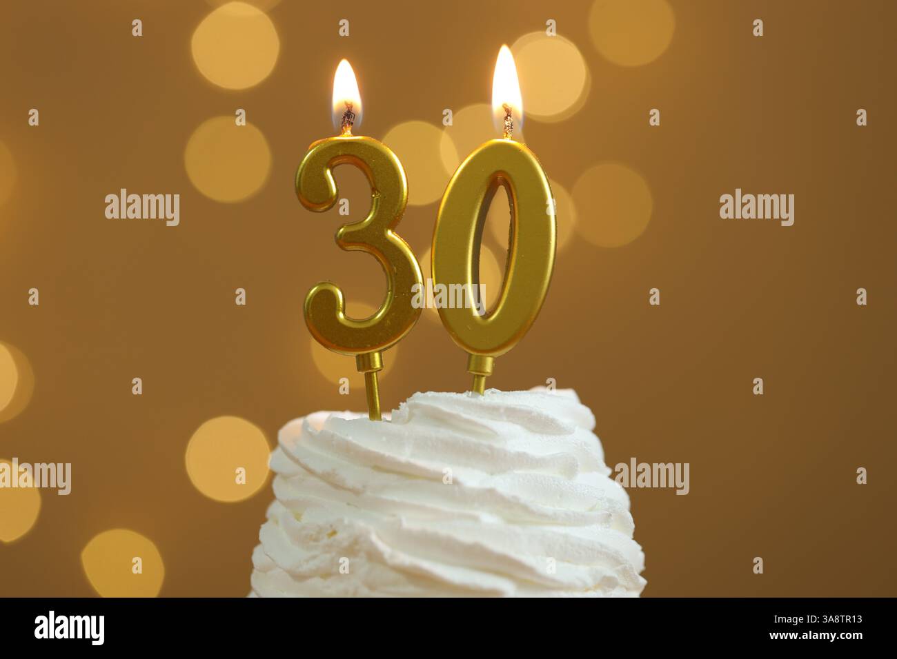 30th birthday. Burning number shaped candles on cupcake against golden ...
