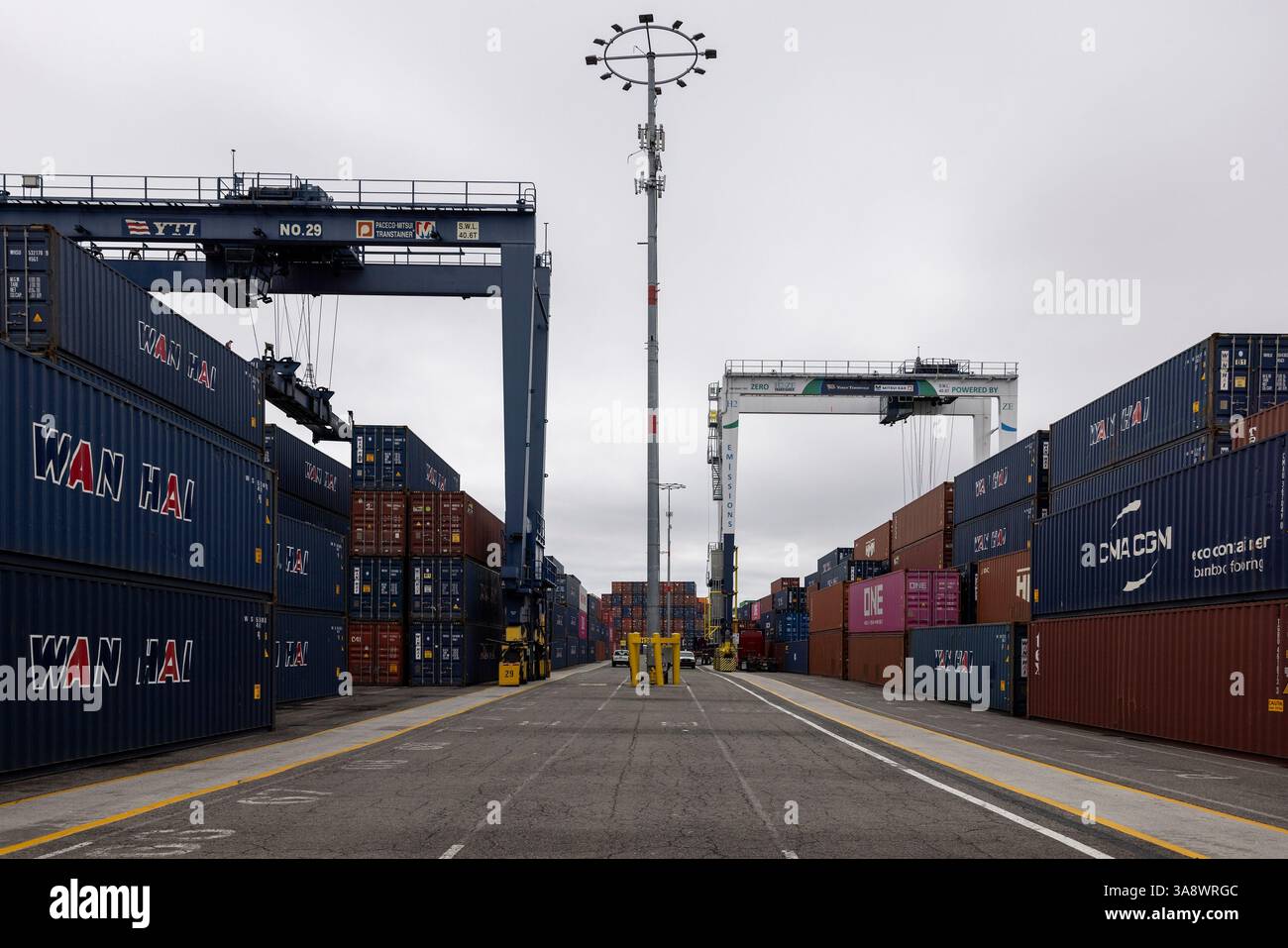 An electric rubber tired gantry, right, loads a container on a truck ...