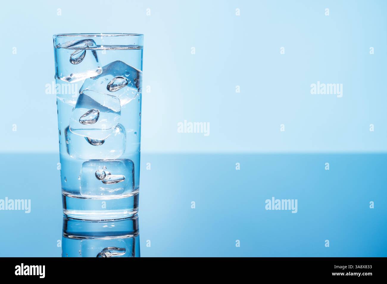 A clear glass filled with chilled water and ice cubes, creating a ...