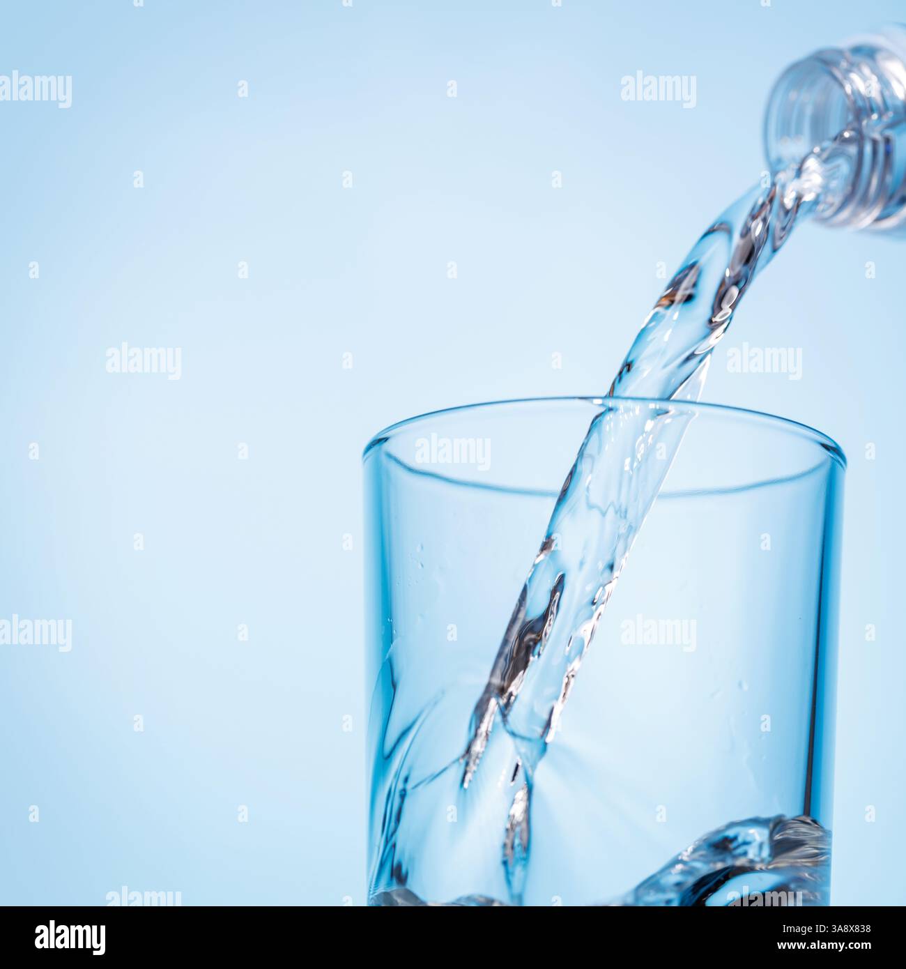Crystal clear water being poured into a transparent glass with ice, creating refreshing ripples ...