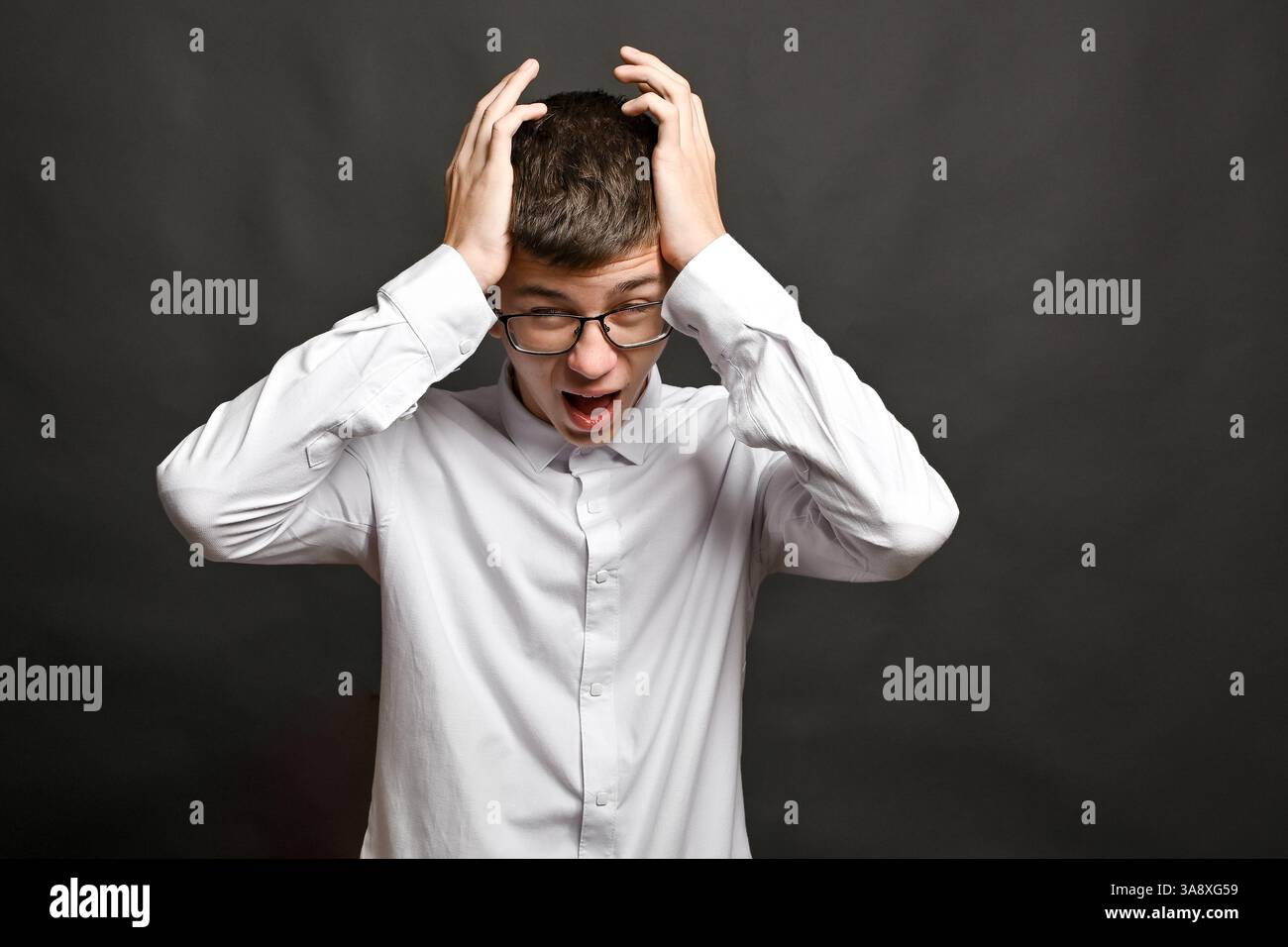 a young man, clutching his head in his hands, screams in pain and anger ...