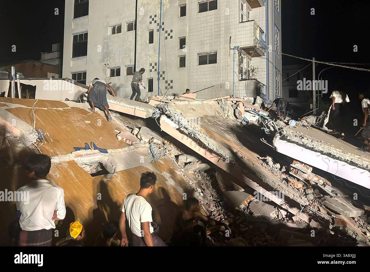 Volunteers work at the site of a building that collapsed after an ...