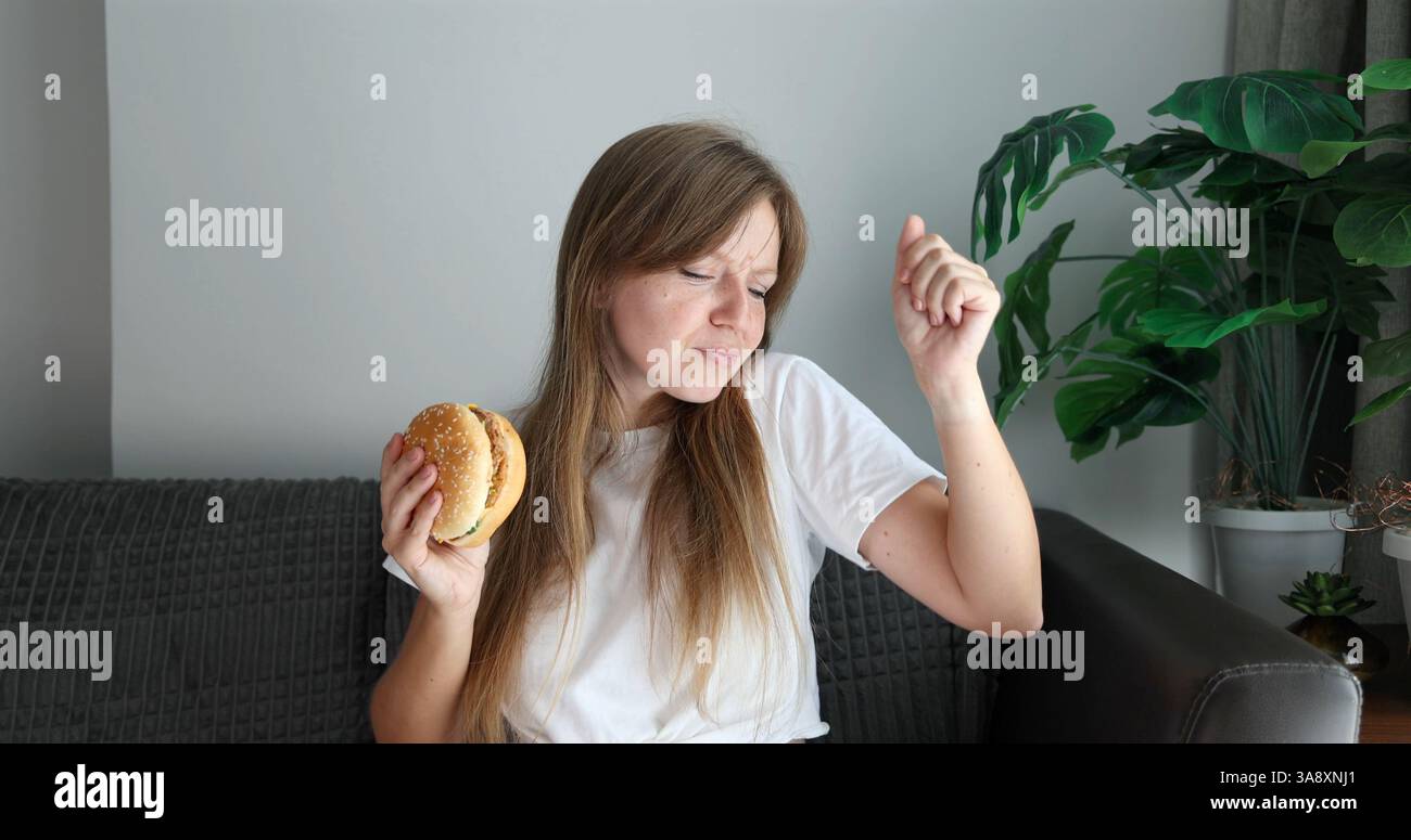 Person listening to music while eating burger, relaxed home setting ...