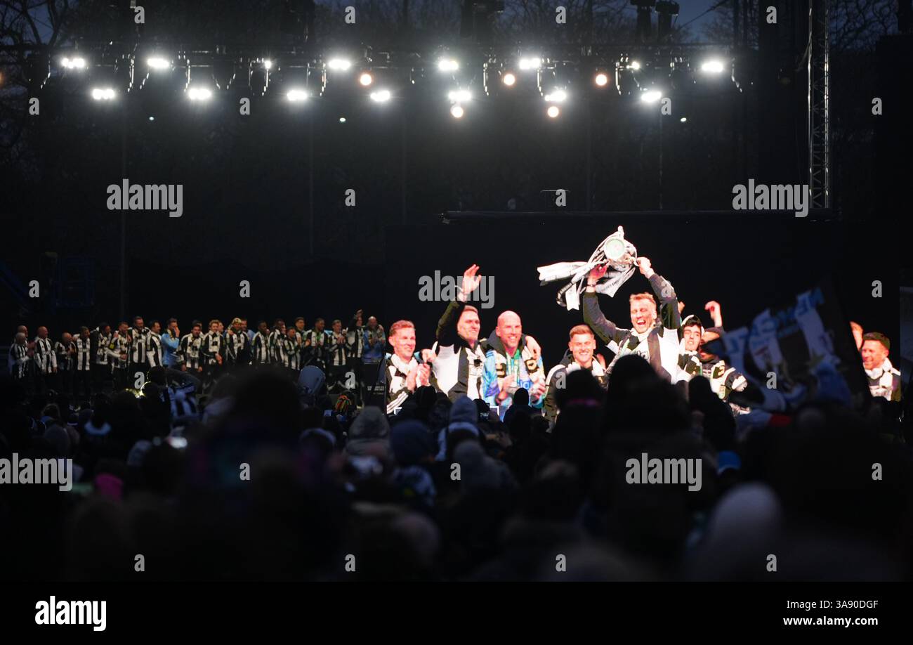 A big screen shows Newcastle United's Dan Burn lift the trophy in front ...