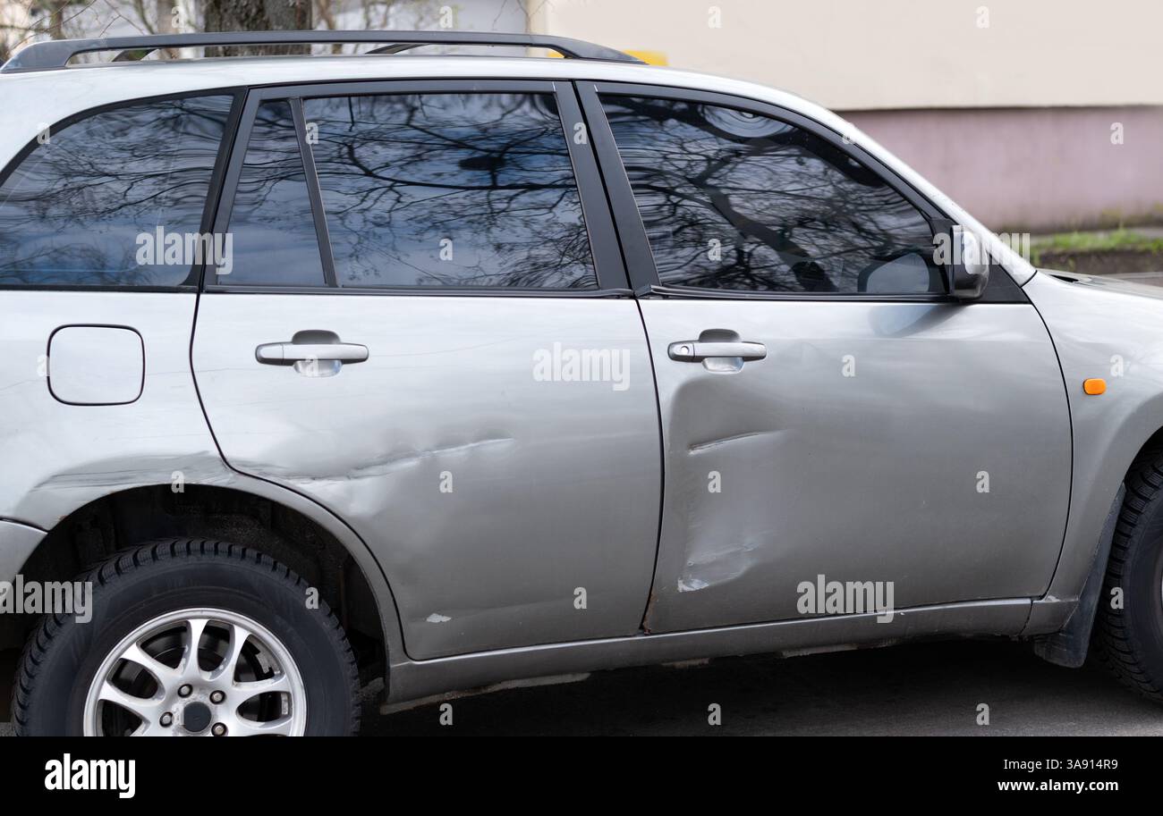 Silver SUV with visible dents and scratches on the side doors, parked ...