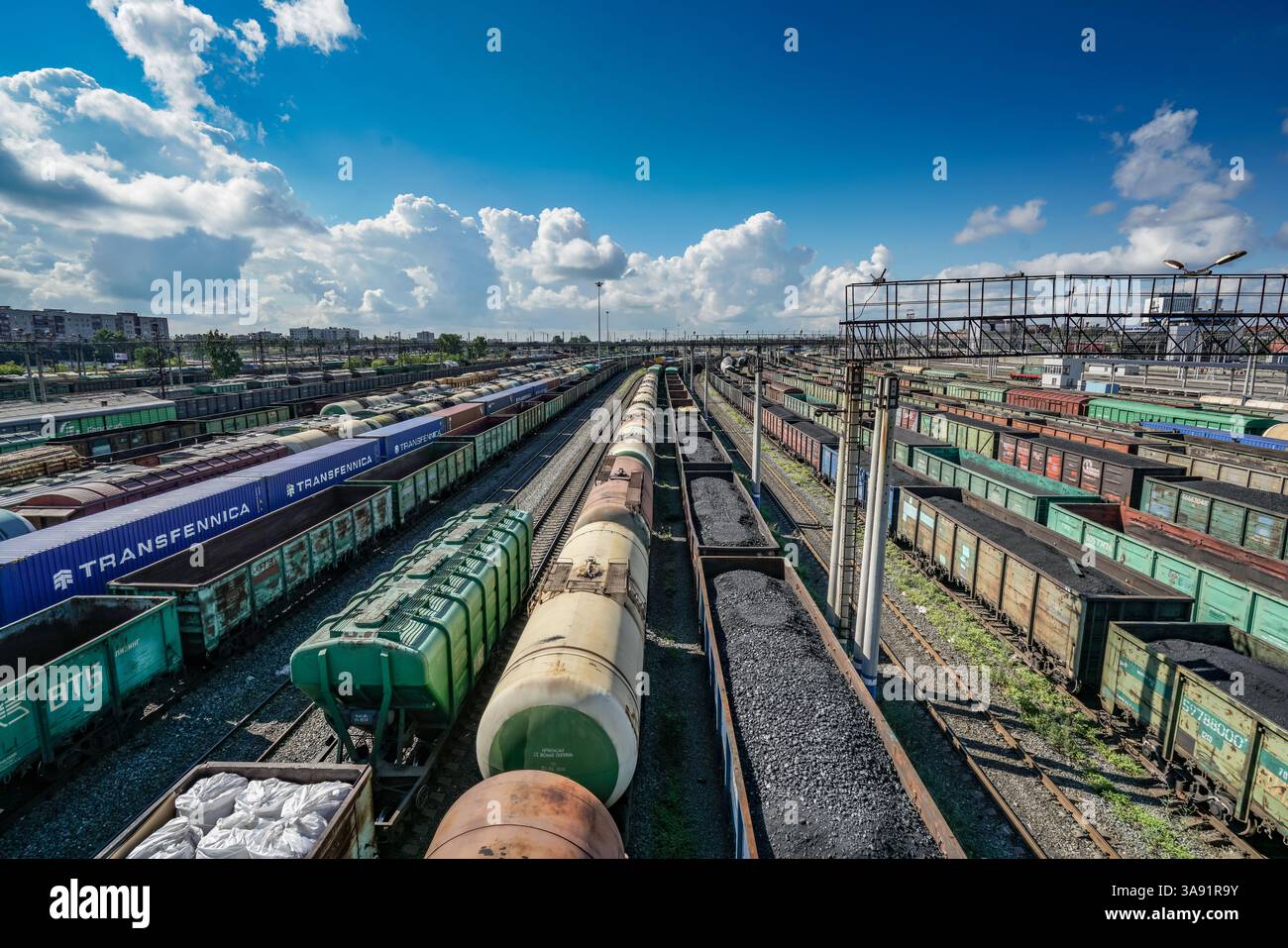 A train yard with many different colored train cars. The train cars are ...