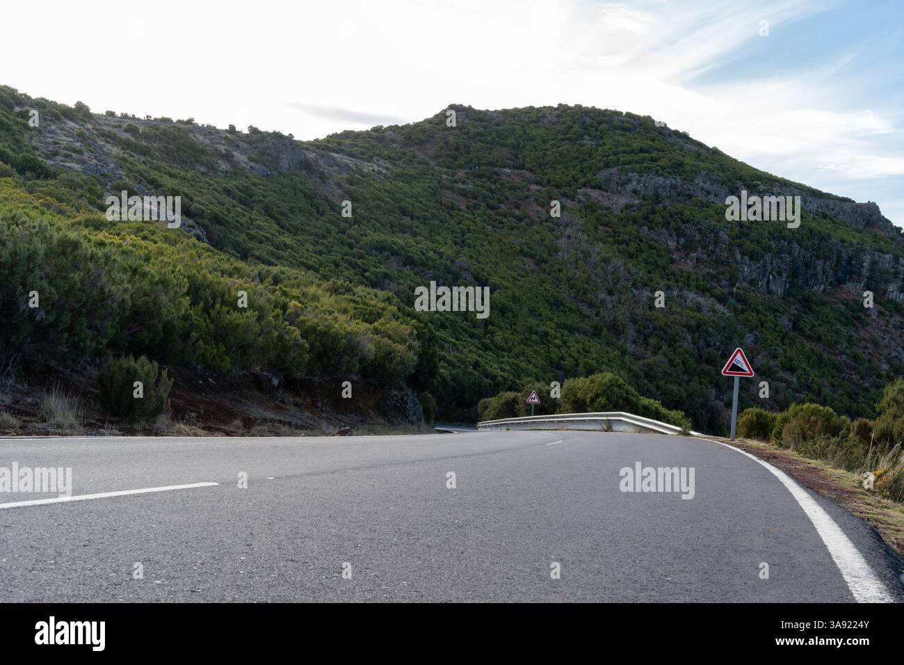 The mountain highway passes through green hills under a bright blue sky ...