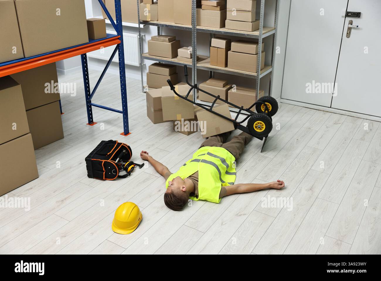 Accident at work. Unconscious man and overturned hand truck on floor in ...