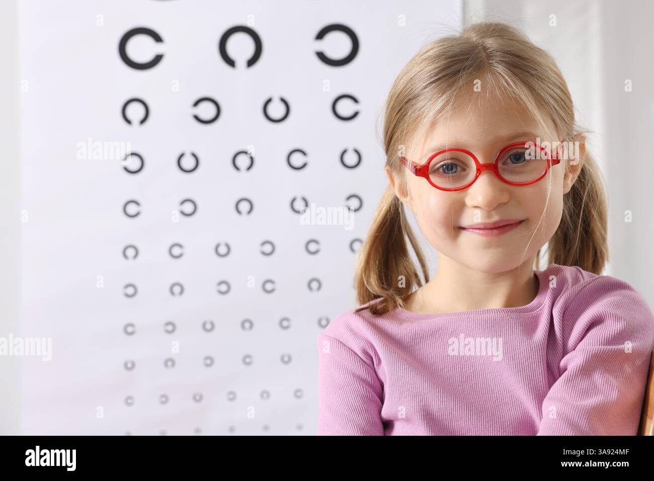 Little girl trying glasses against vision test chart Stock Photo - Alamy