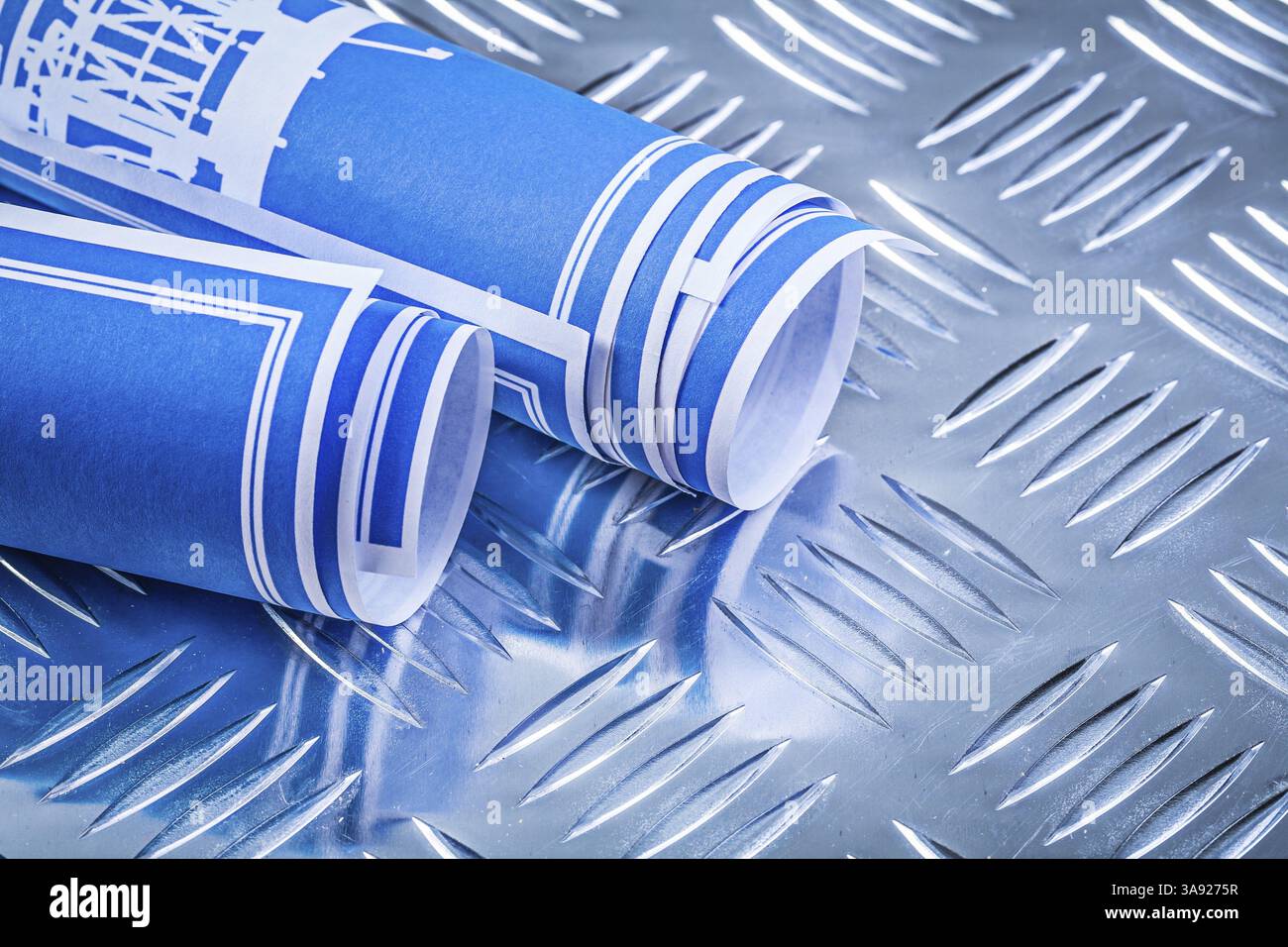 Blue rolled up engineering drawings on fluted metal background ...