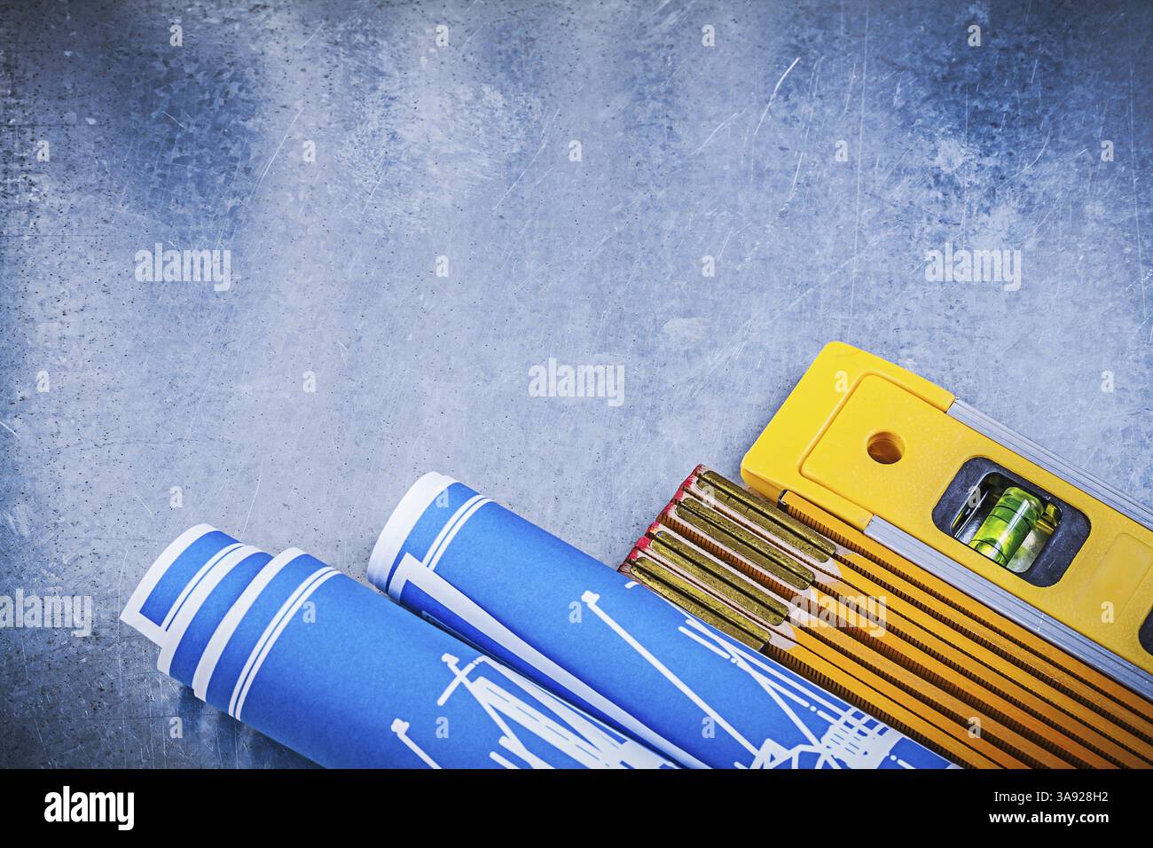 Wooden meter blue rolled construction drawings level on metallic ...