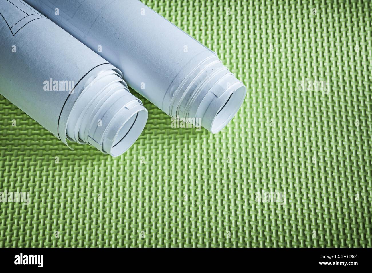 Rolled engineering drawings on green background construction concept ...