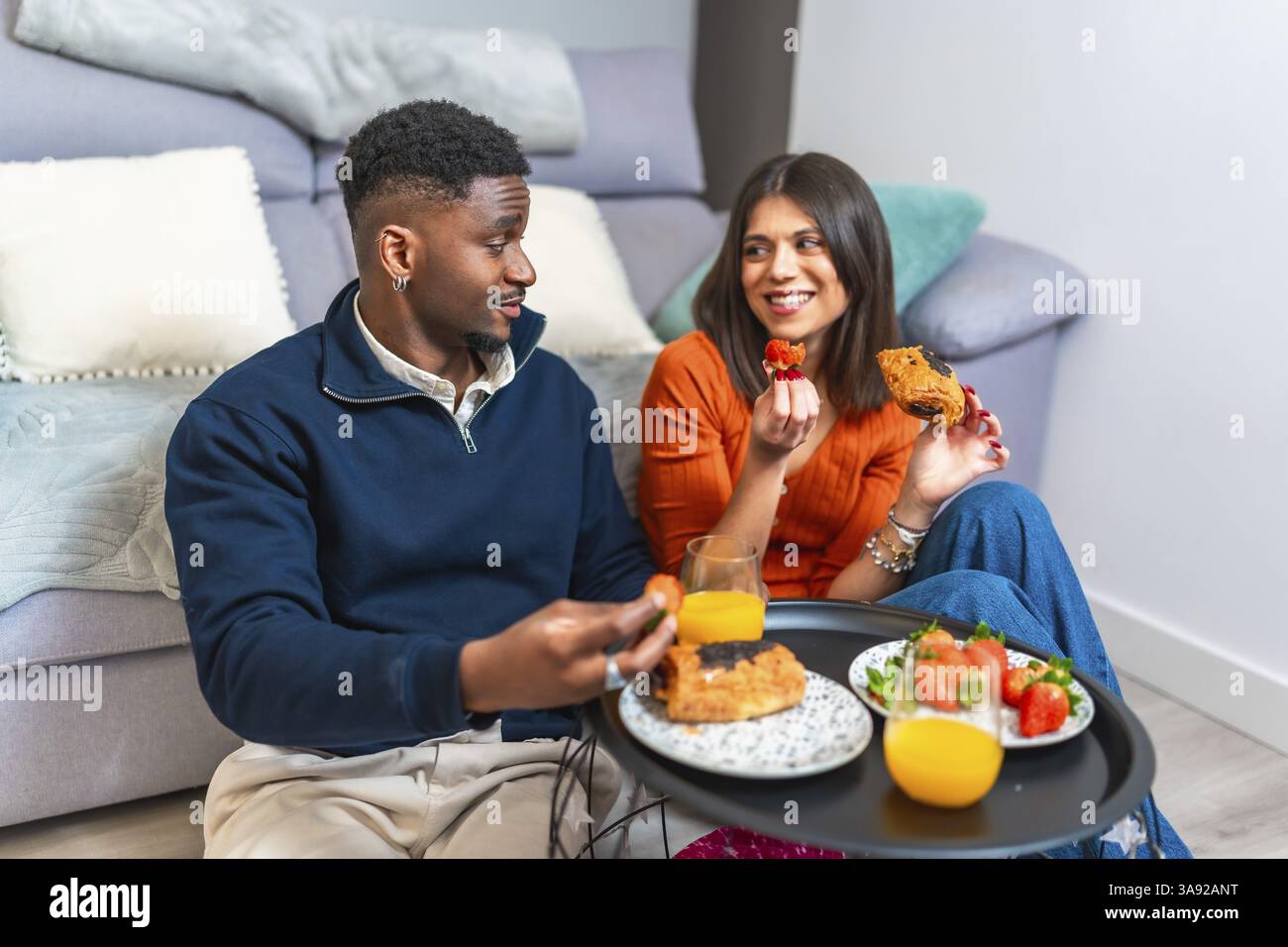 Couple sharing a cozy breakfast at home, enjoying fresh fruit, pastries ...