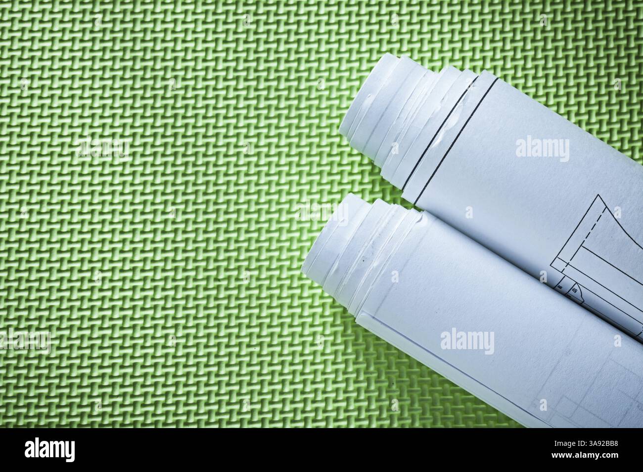 Rolled construction plans on green background building concept Stock ...