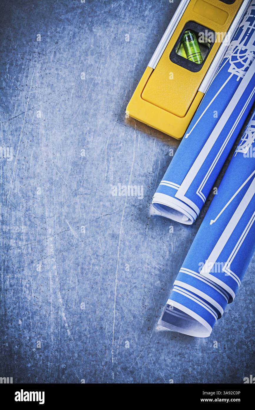Rolled up blue blueprints construction level on metallic background ...