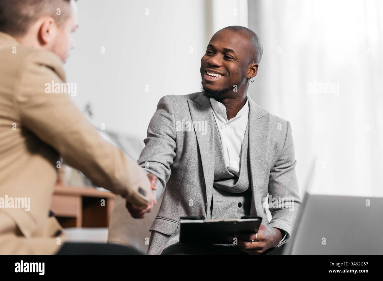 Cheerful african male business partners shaking hands at workplace ...