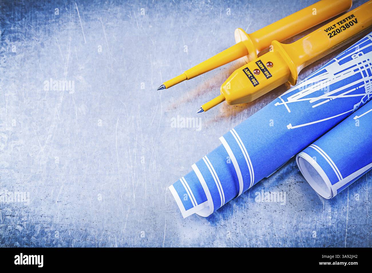 Yellow electrical tester blue blueprints on metallic background ...