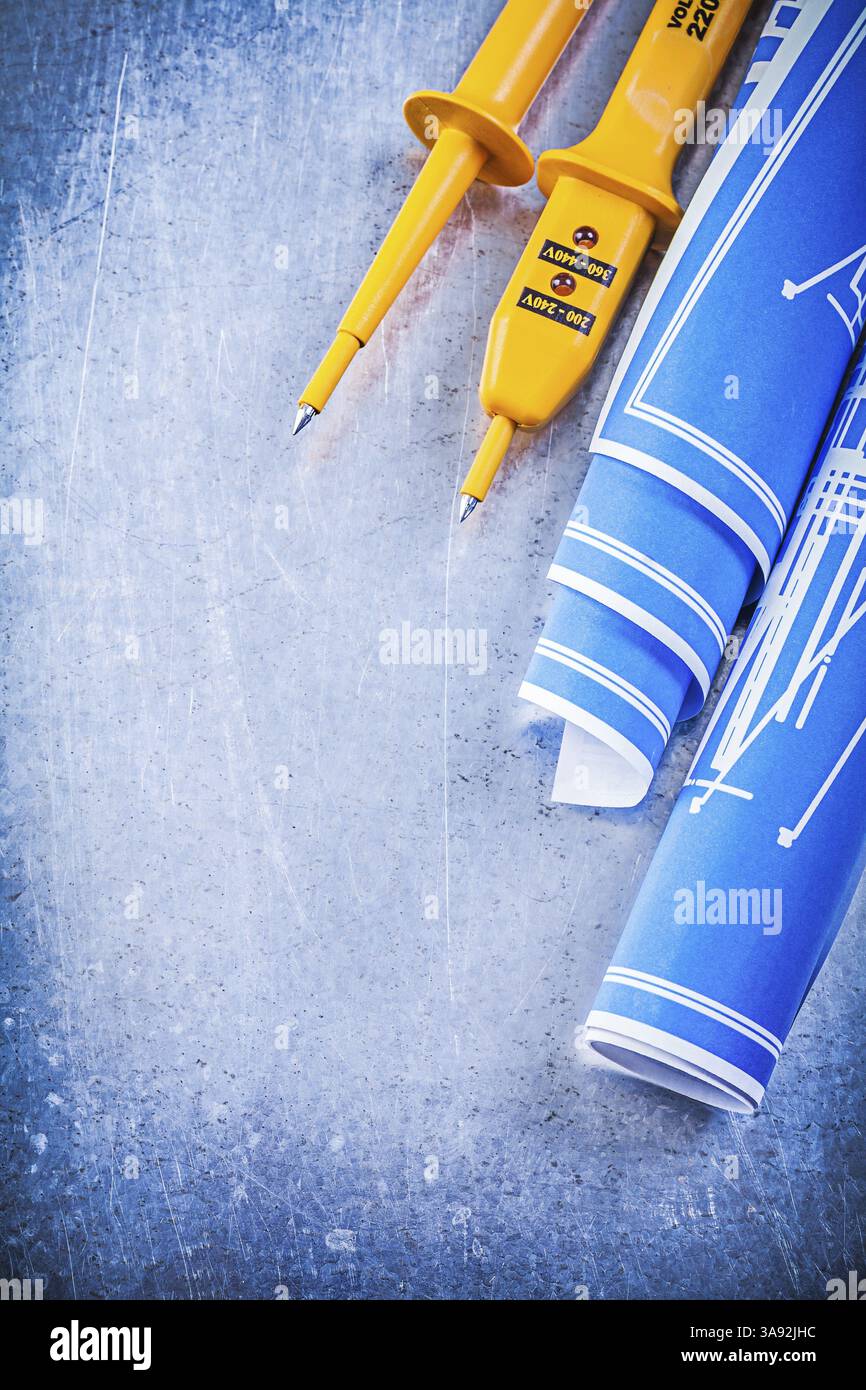 Yellow electrical tester blue construction plans on metallic background ...