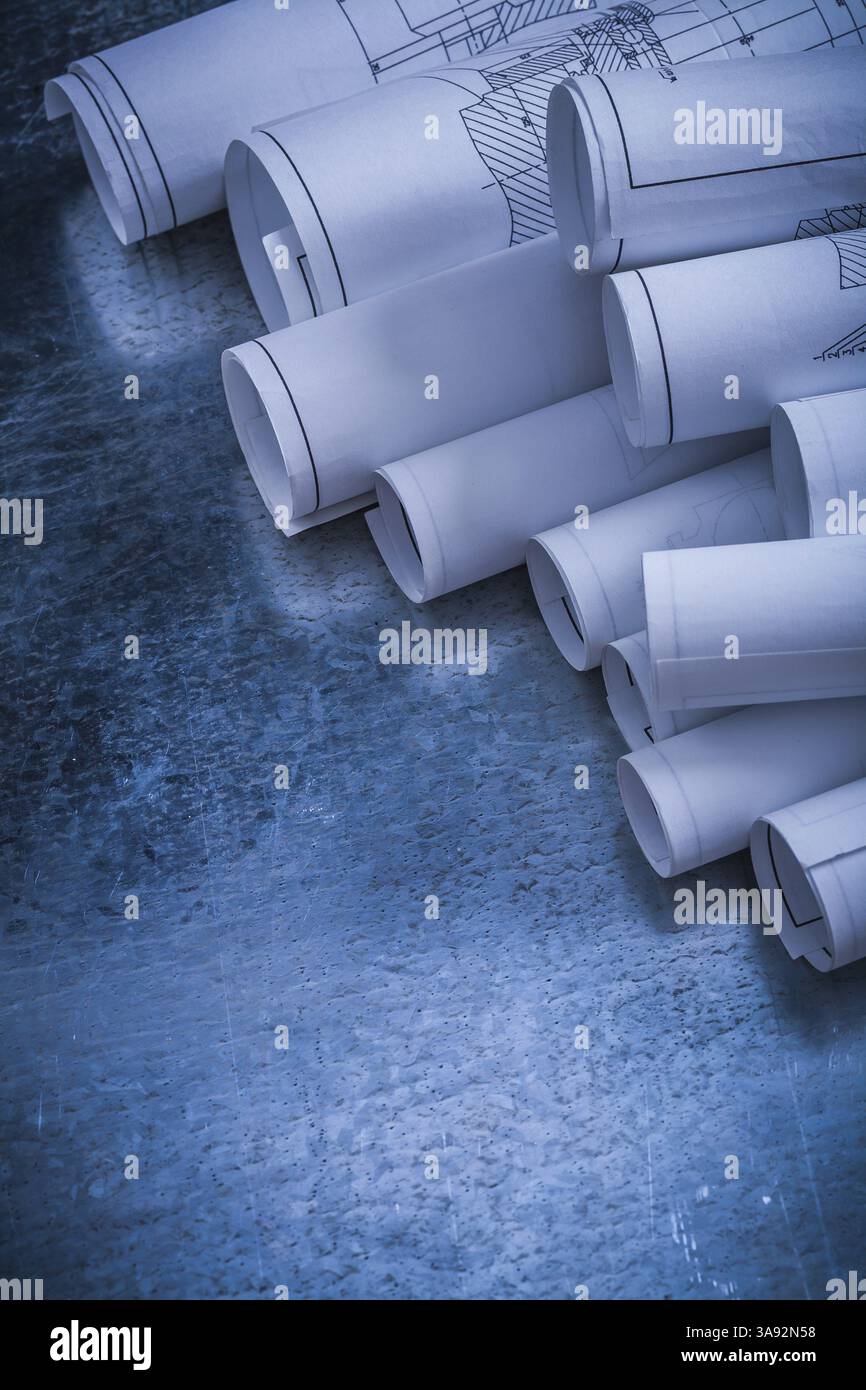 Metallic surface with variety of rolled up white blueprints building ...