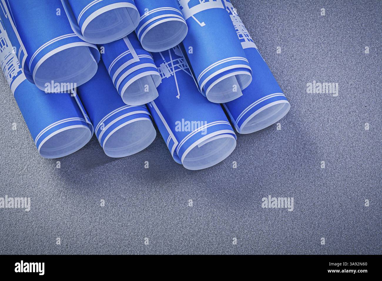Stack of blue rolled up construction plans on grey background ...