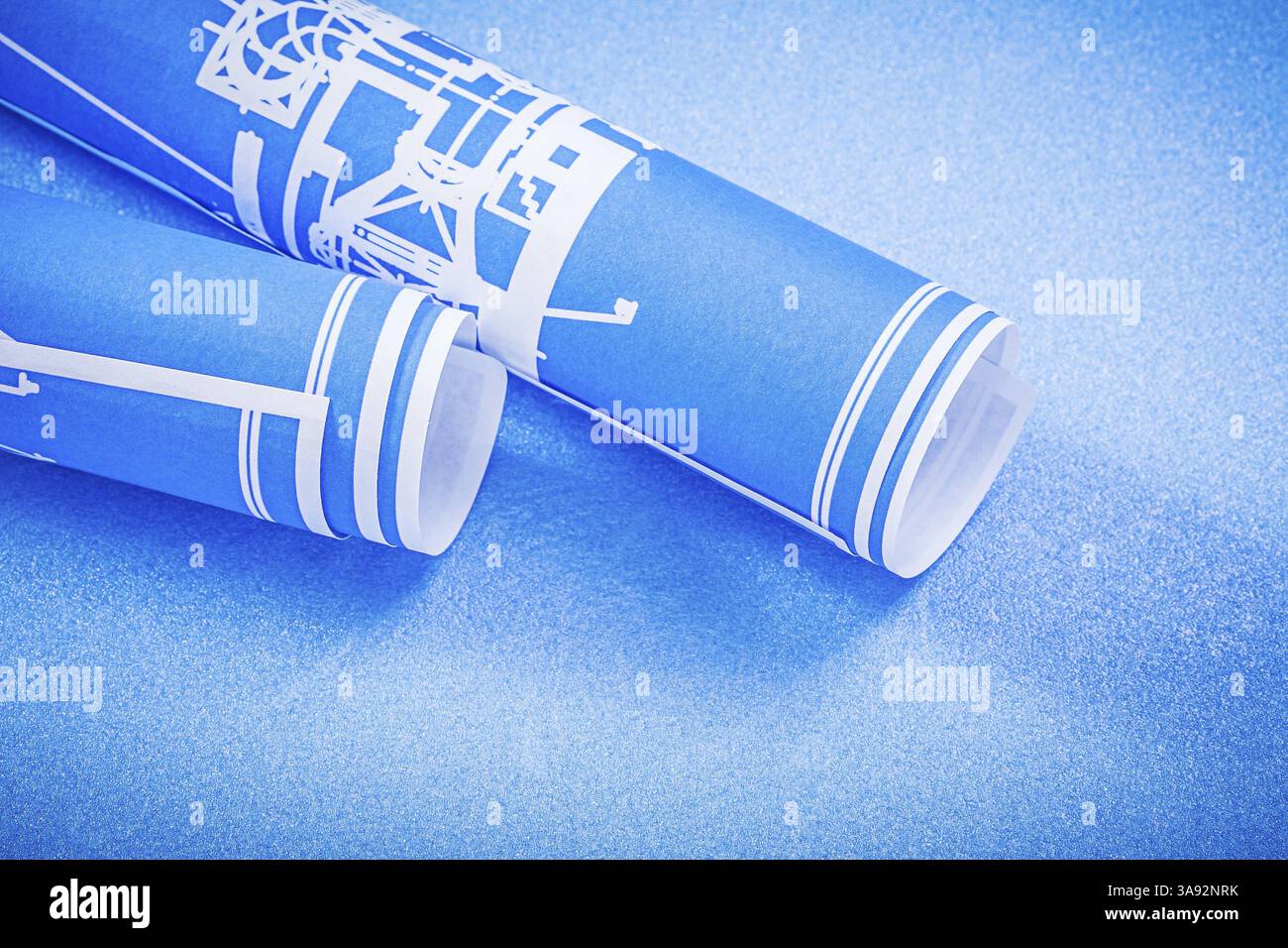Rolled engineering drawings on blue background construction concept ...