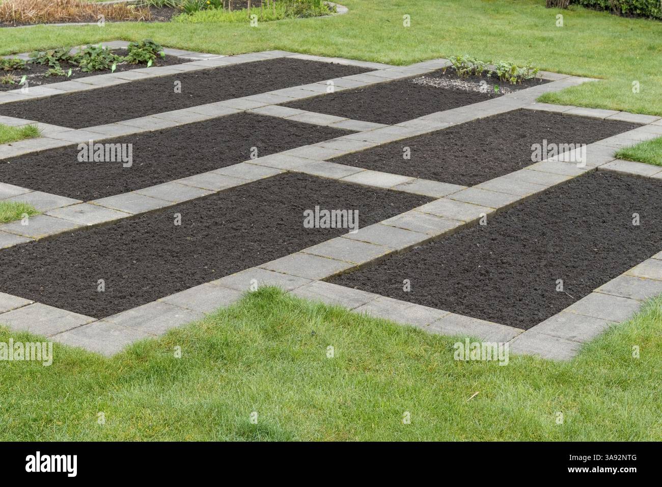 Rectangular raised garden beds filled with dark soil create a geometric ...