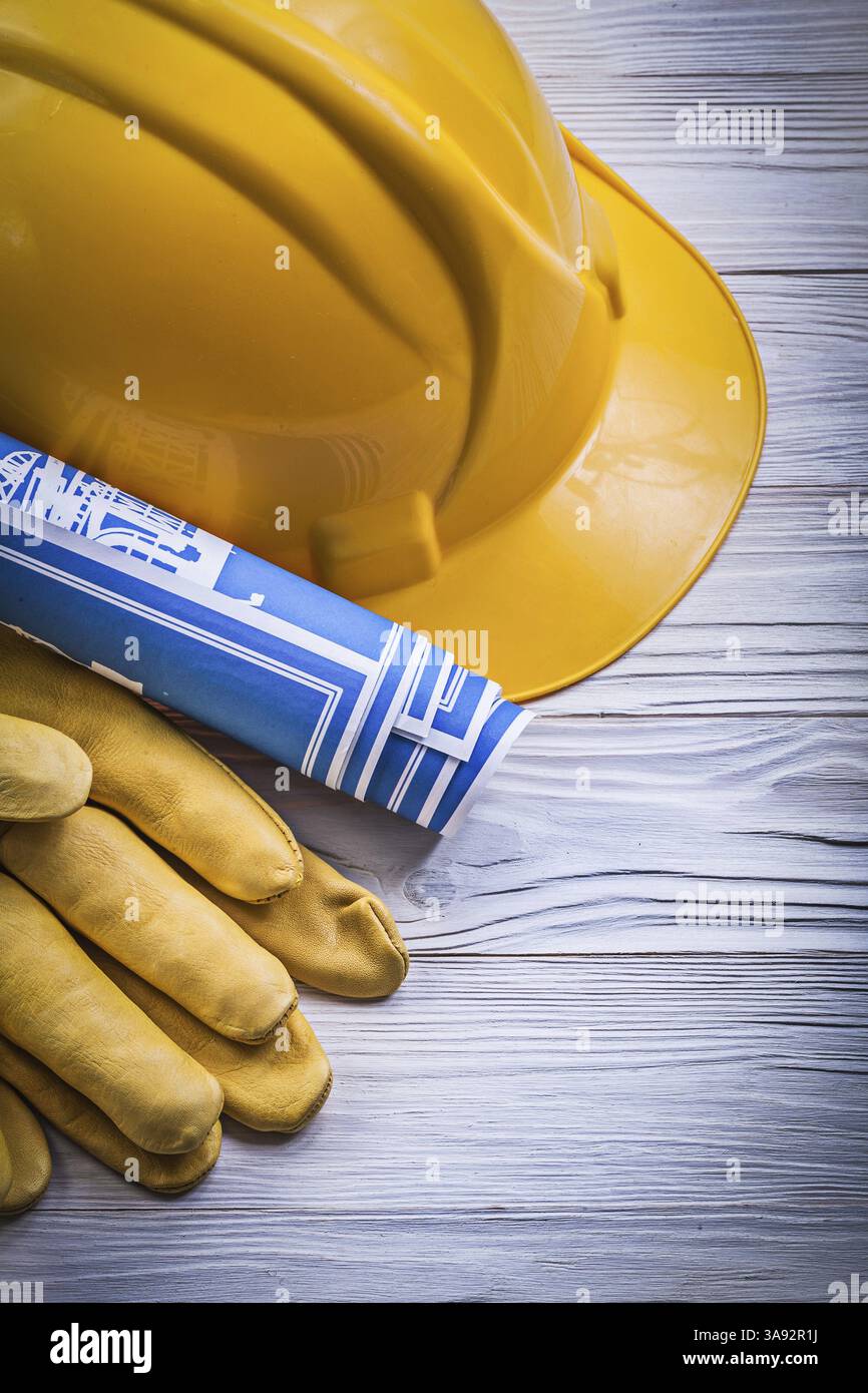 Set of safety gloves hard hat blue engineering drawings on wood board ...