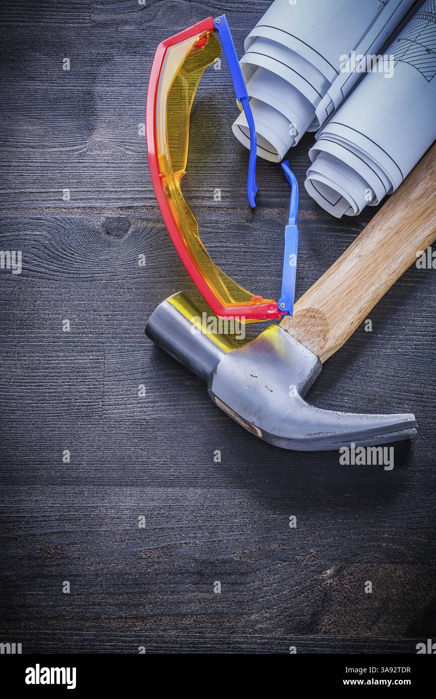 Vertical view rolled blueprints hammer goggles on wood board Stock ...