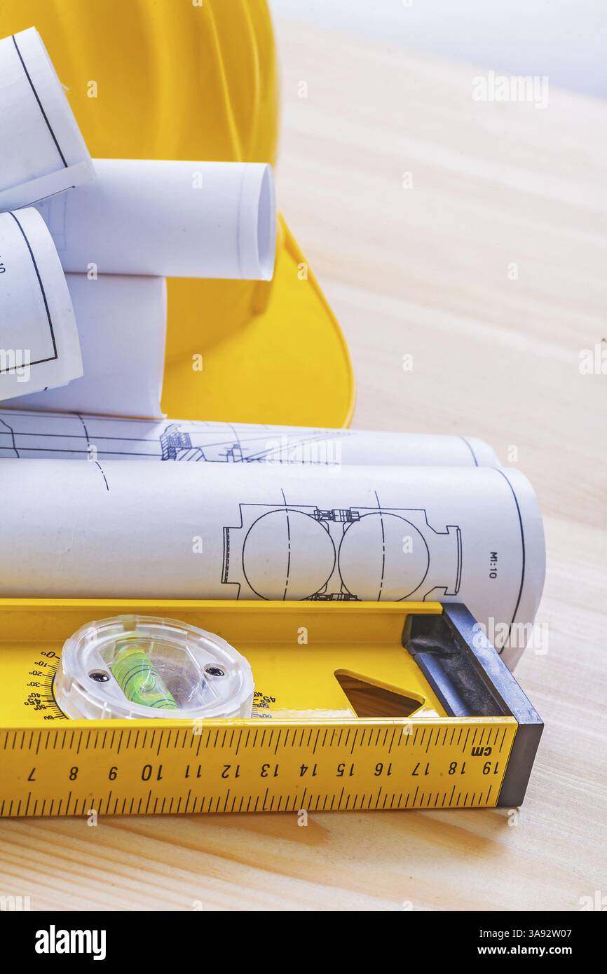 Level rolls of blueprints and helmet on wooden boards construction ...