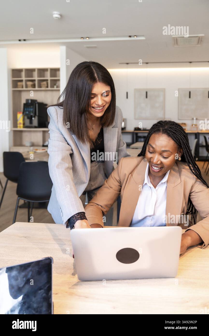 Two businesswomen collaborating on a laptop, enjoying a productive ...