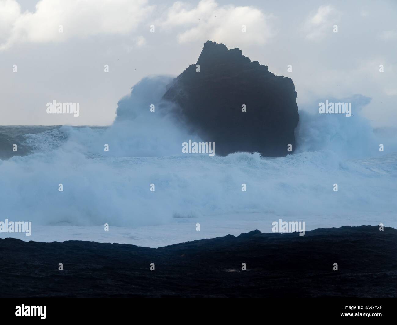 VALAHNUKAMOL, Massive ocean waves crashing against a rugged sea stack ...