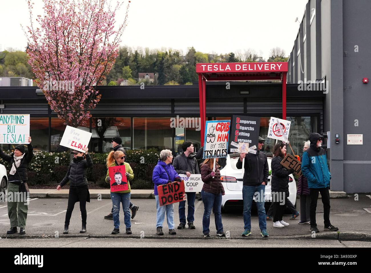 People wave signs outside of a Tesla service center location during a ...