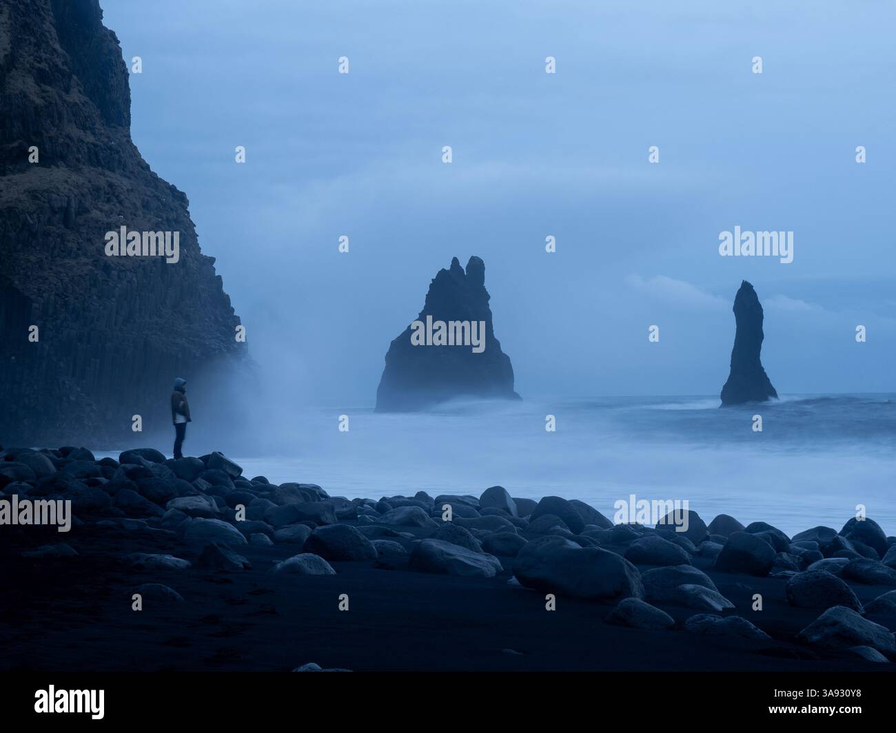 Reynisfjara Beach, Iceland: A solitary figure faces the powerful waves ...