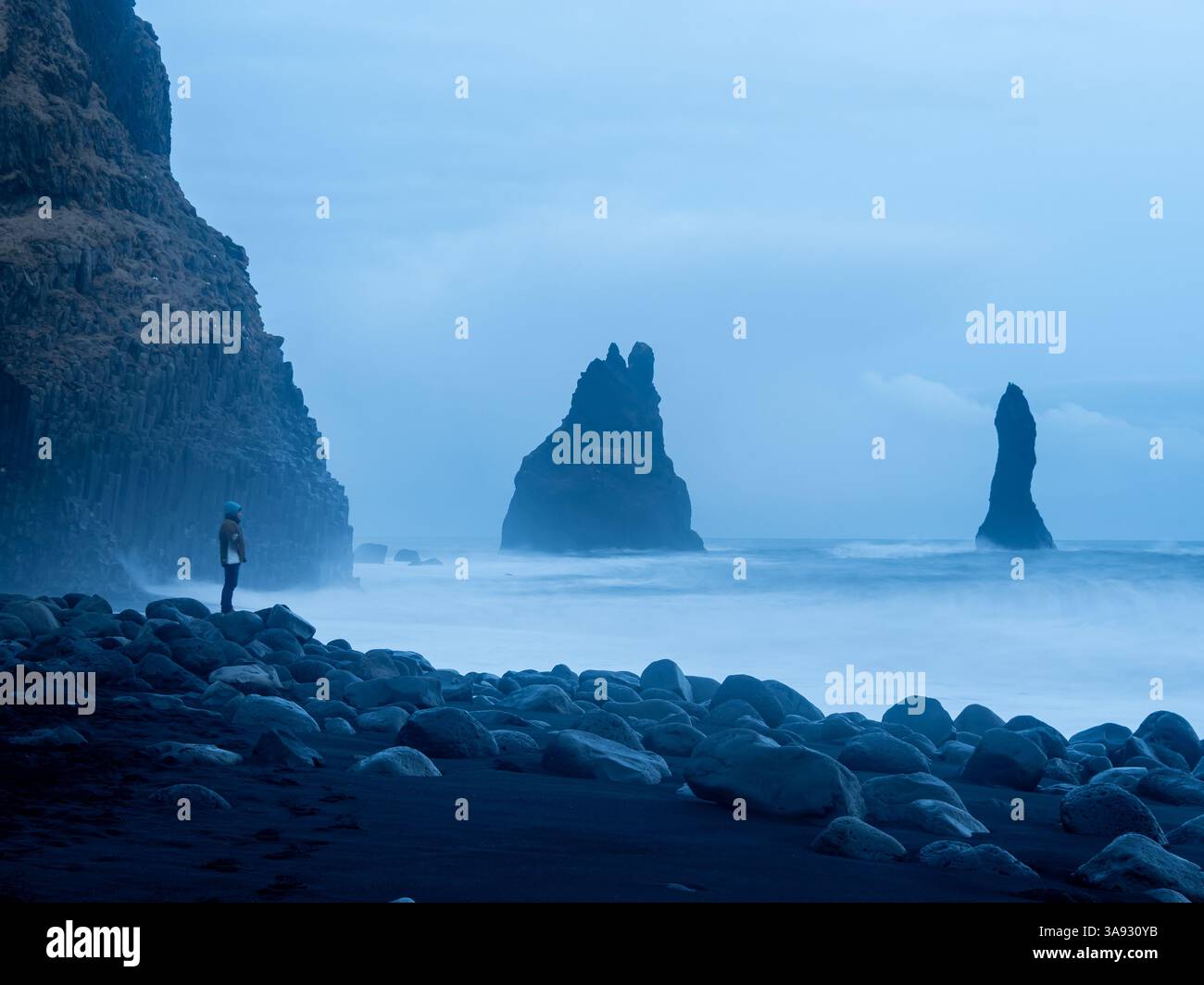 Reynisfjara Beach, Iceland: A lone figure stands against crashing waves ...