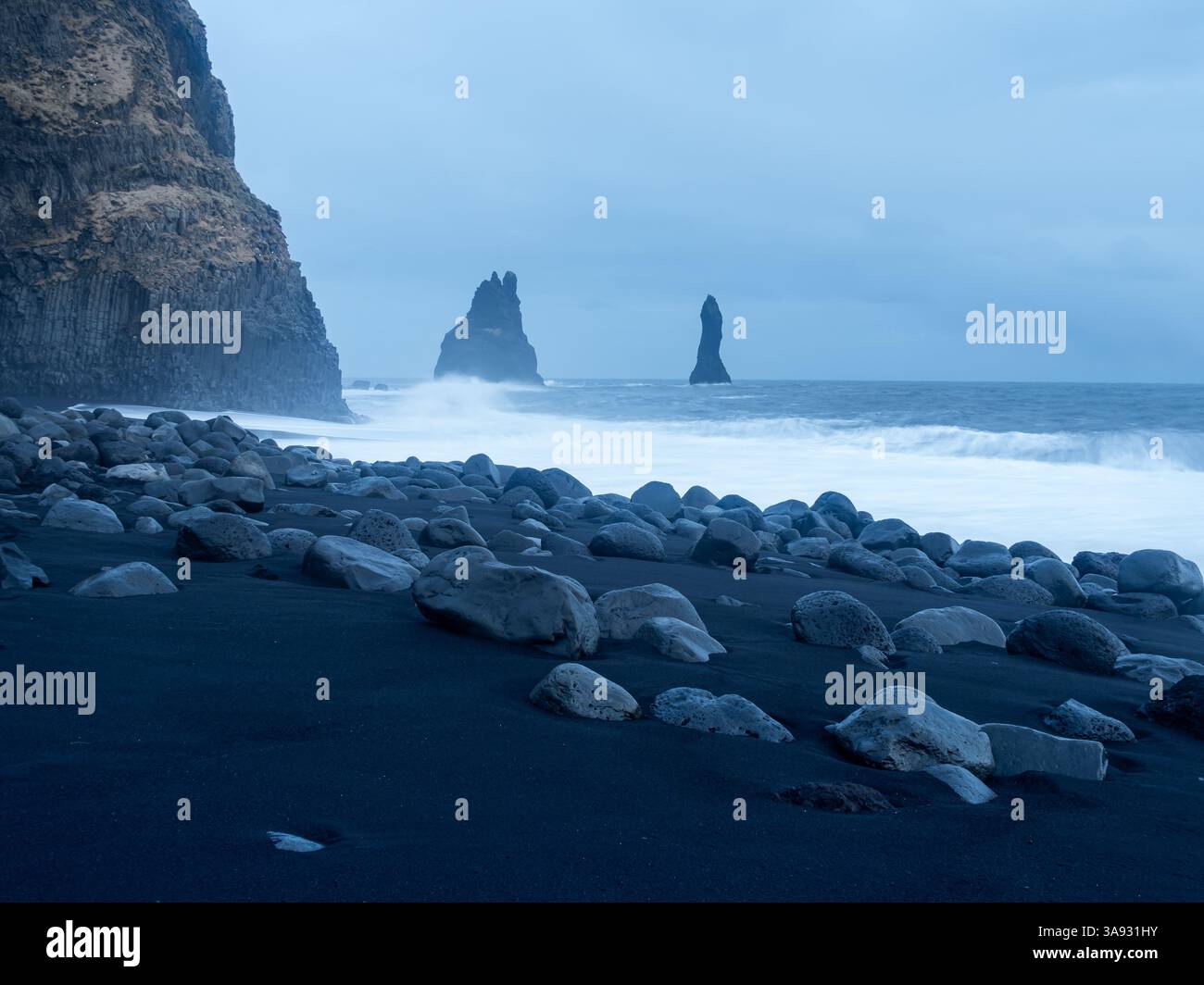Reynisfjara Beach at dusk with rugged basalt columns and Reynisdrangar ...