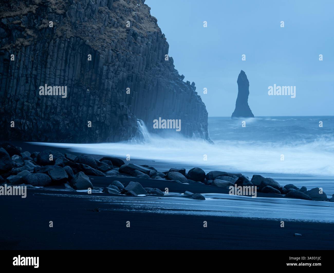 Reynisfjara Beach at twilight, featuring the iconic Reynisdrangar sea stack and basalt column ...