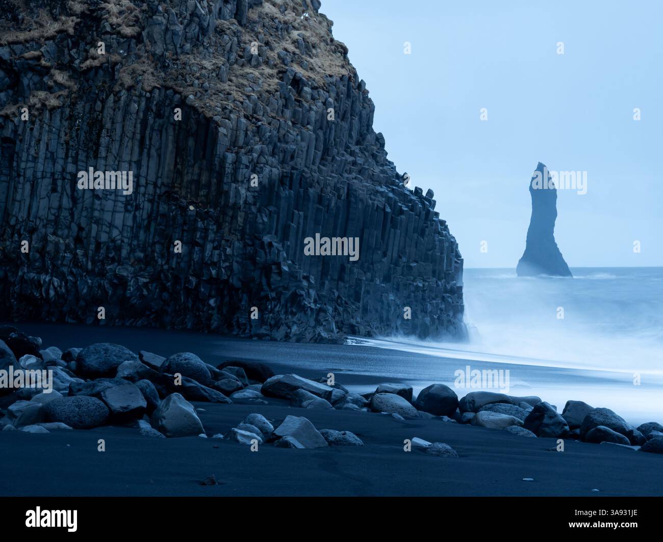 Reynisfjara Beach at twilight, featuring the iconic Reynisdrangar sea stack and basalt column ...