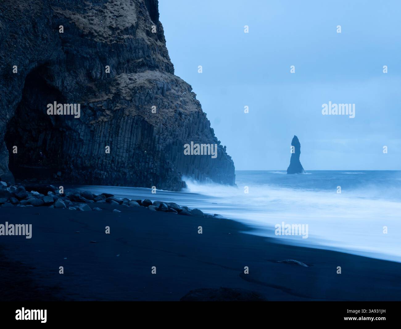 Reynisfjara Beach at twilight, featuring the iconic Reynisdrangar sea stack and basalt column ...