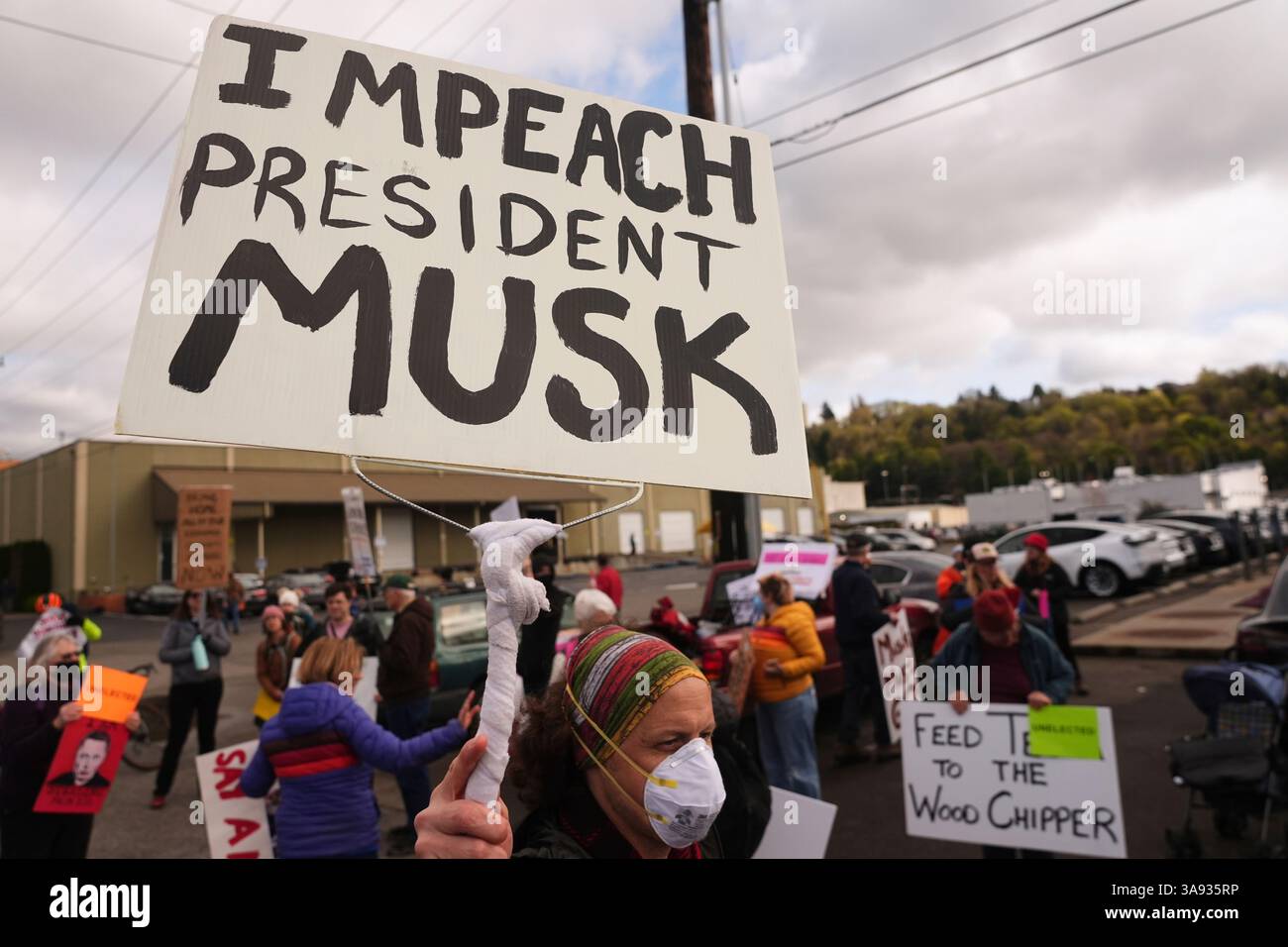 A person waves an "Impeach President Musk" sign during a protest ...