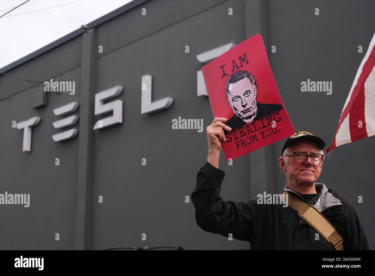 A person waves a sign depicting Elon Musk during a protest against Musk ...