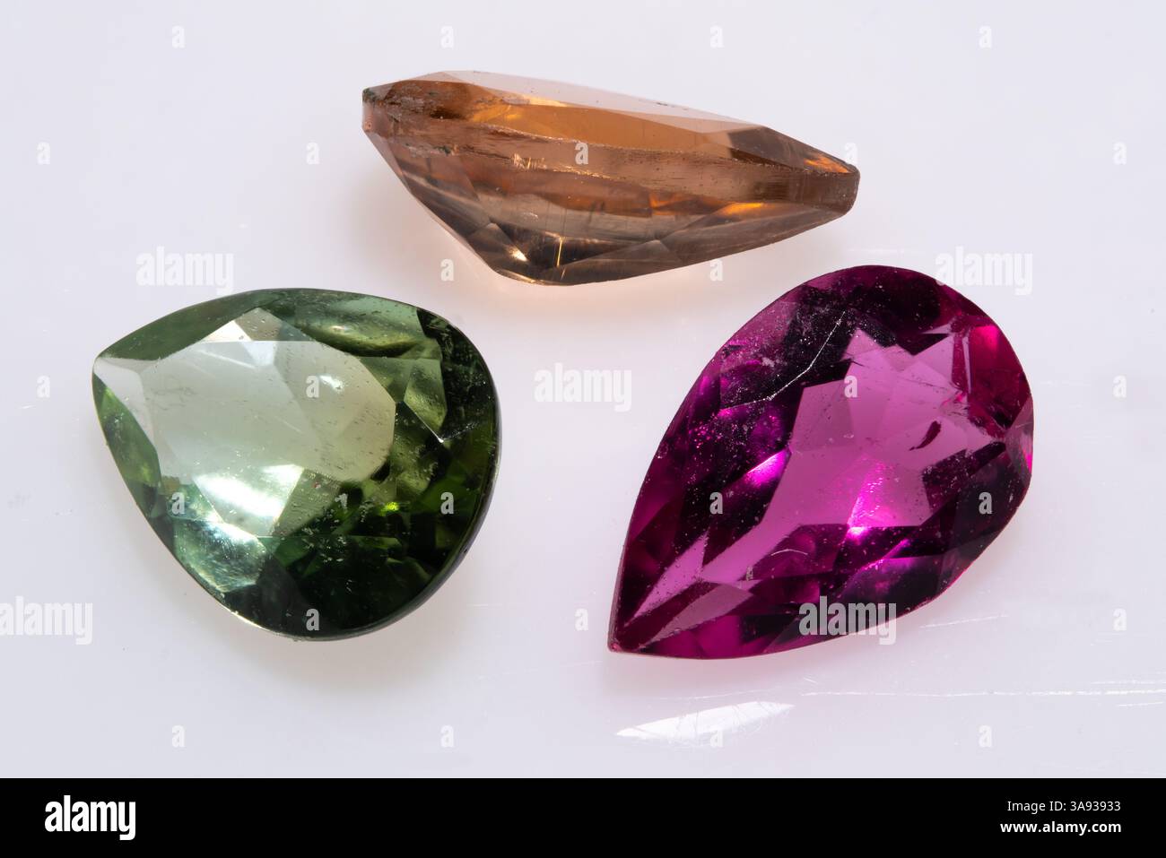 Three Faceted Gemstones in Green, Purple, and Amber Shades on White ...