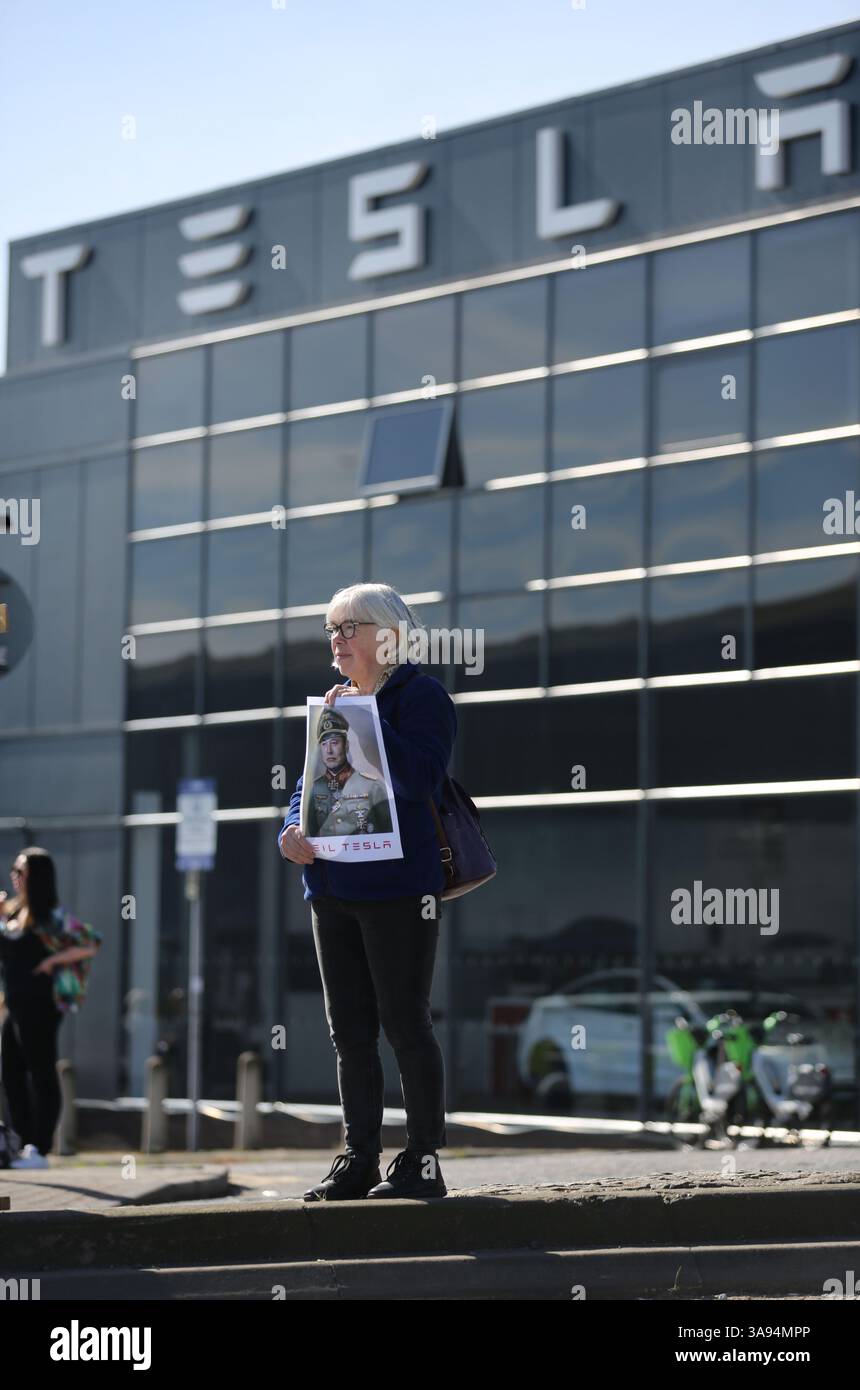 A protester holds a placard showing Elon Musk in a Nazi uniform outside ...