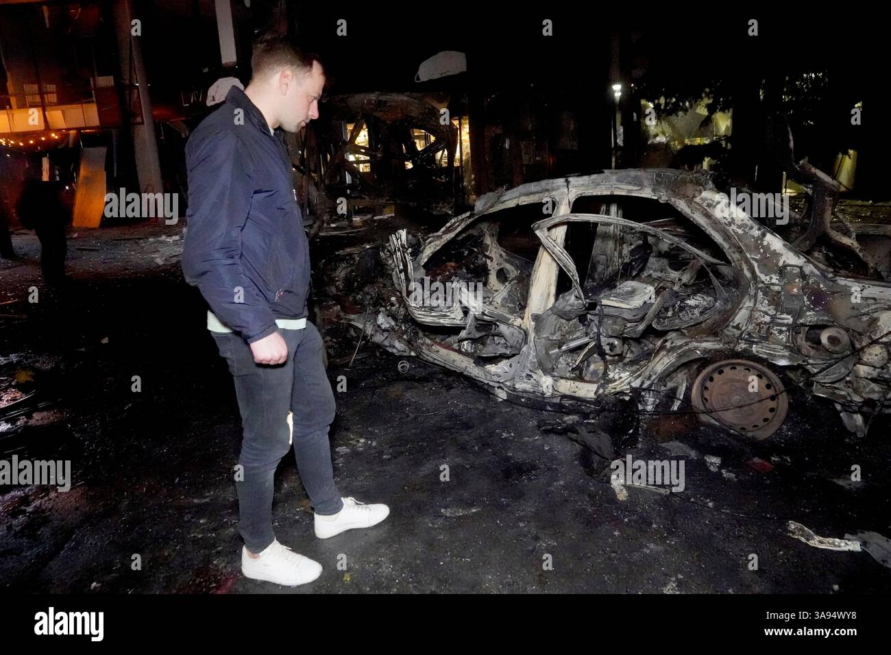 A man looks at a car destroyed in a Russian strike on Kharkiv, Ukraine ...