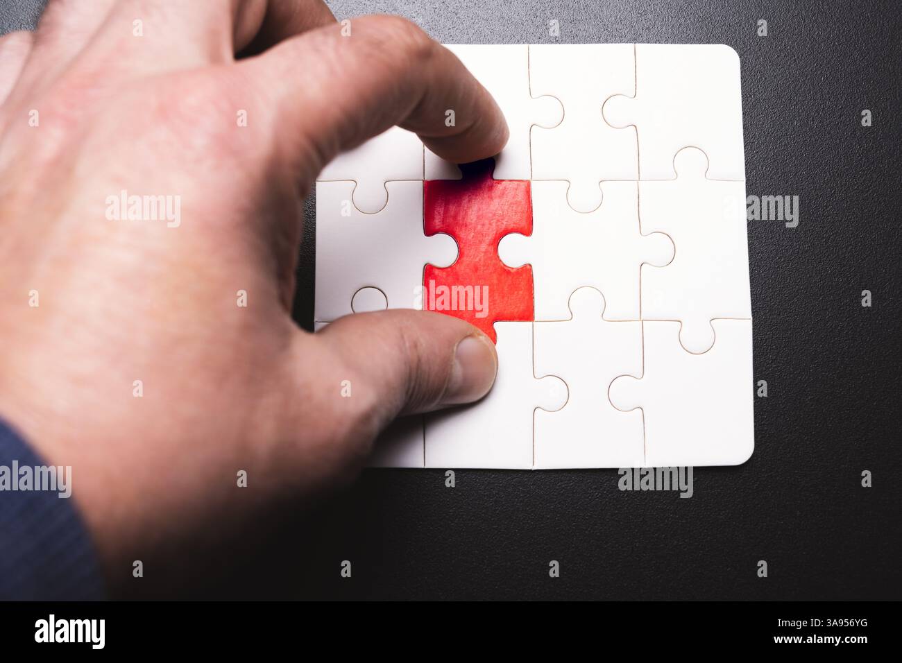 A hand is trying to solve a puzzle with a red piece missing. The puzzle ...