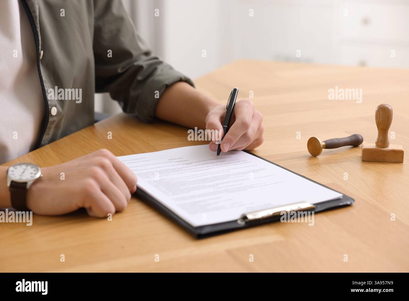 Client signing notarial document at wooden table in office, closeup ...