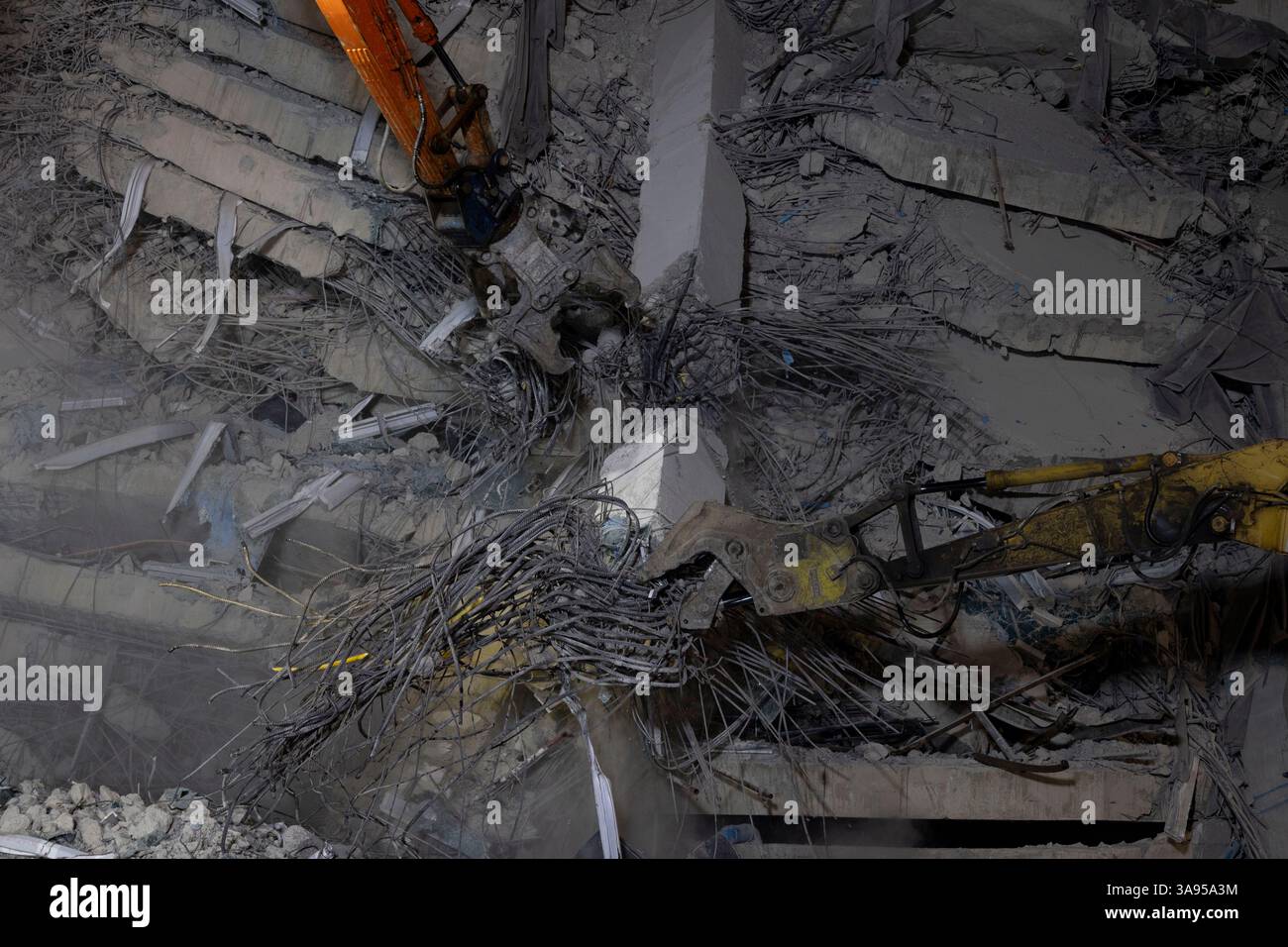 Rescuers use heavy machinery at the site of a collapsed under ...