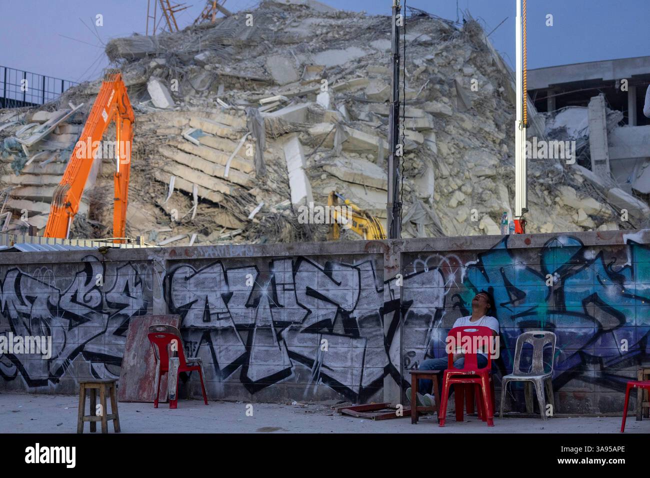 Relatives of victims wait as rescuers work at the site of a collapsed ...